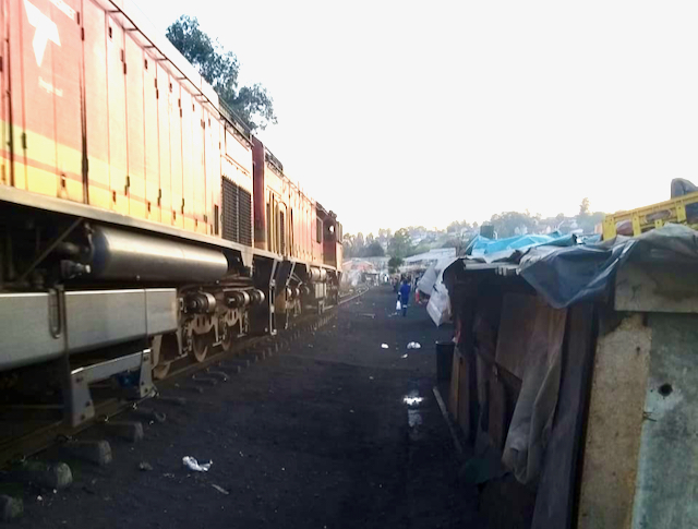 Families live in shacks on a railway line after housing project ...
